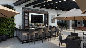 Uma área de bar ao ar livre com balcão, banquetas e guarda-sóis.