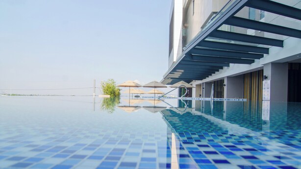 Um hotel moderno com piscina, área de estar externa e vista clara do céu.