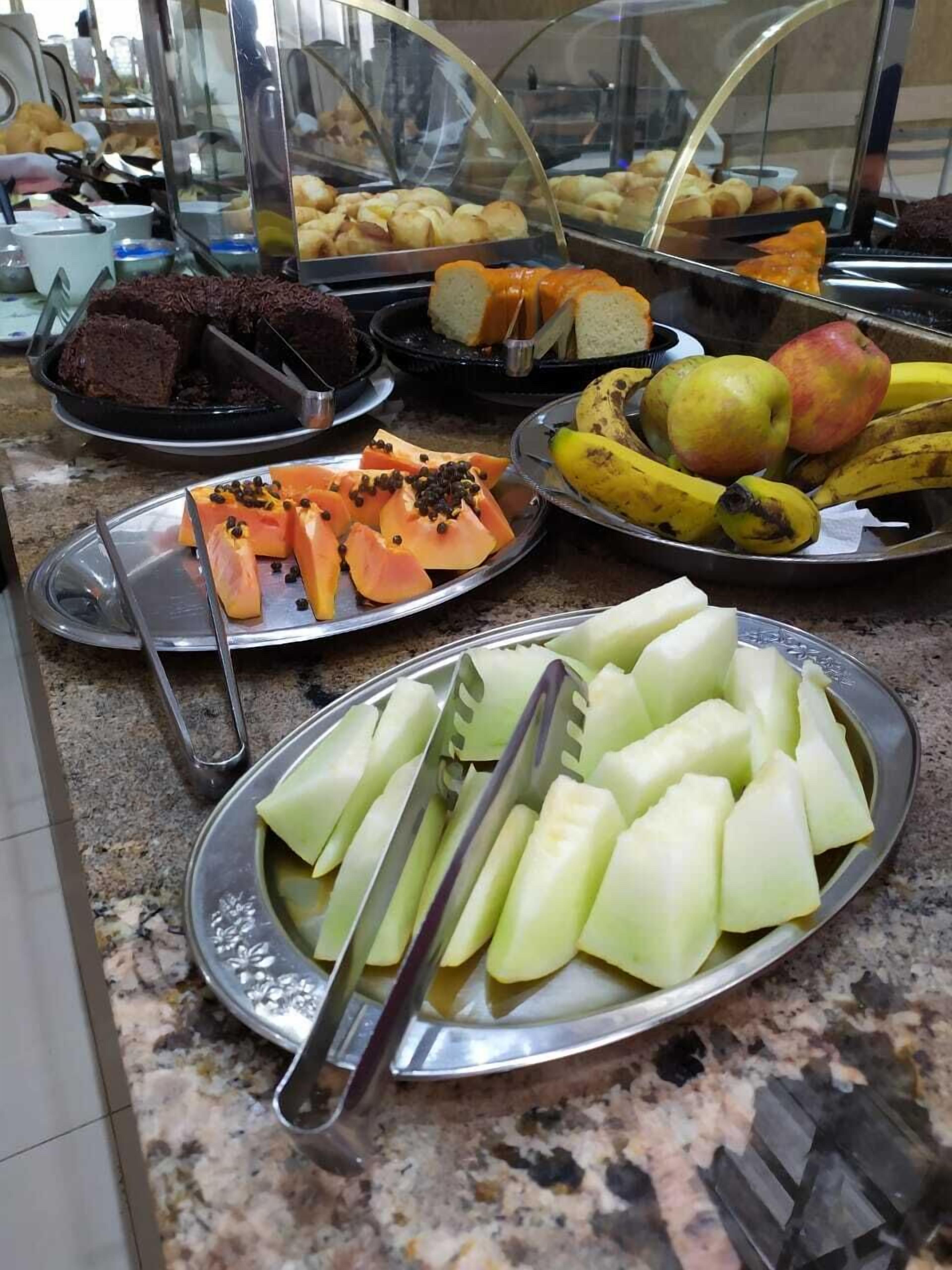 Buffet com diversas opções de comida, incluindo pão, frutas e legumes.