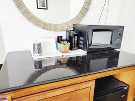 Uma bancada de cozinha com uma cafeteira, uma xícara e um pacote de café.