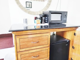 Uma cozinha compacta com micro-ondas, cafeteira e pequena geladeira.