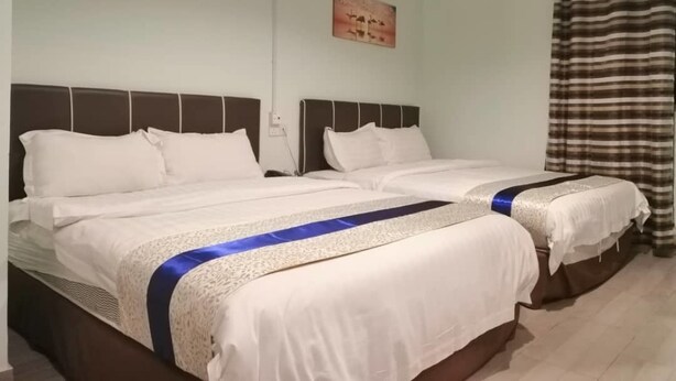 Quarto de hotel com duas camas, um quadro na parede e cortina listrada.