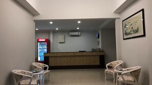 Uma área de recepção com refrigerador Coca-Cola, um balcão de atendimento e duas cadeiras.