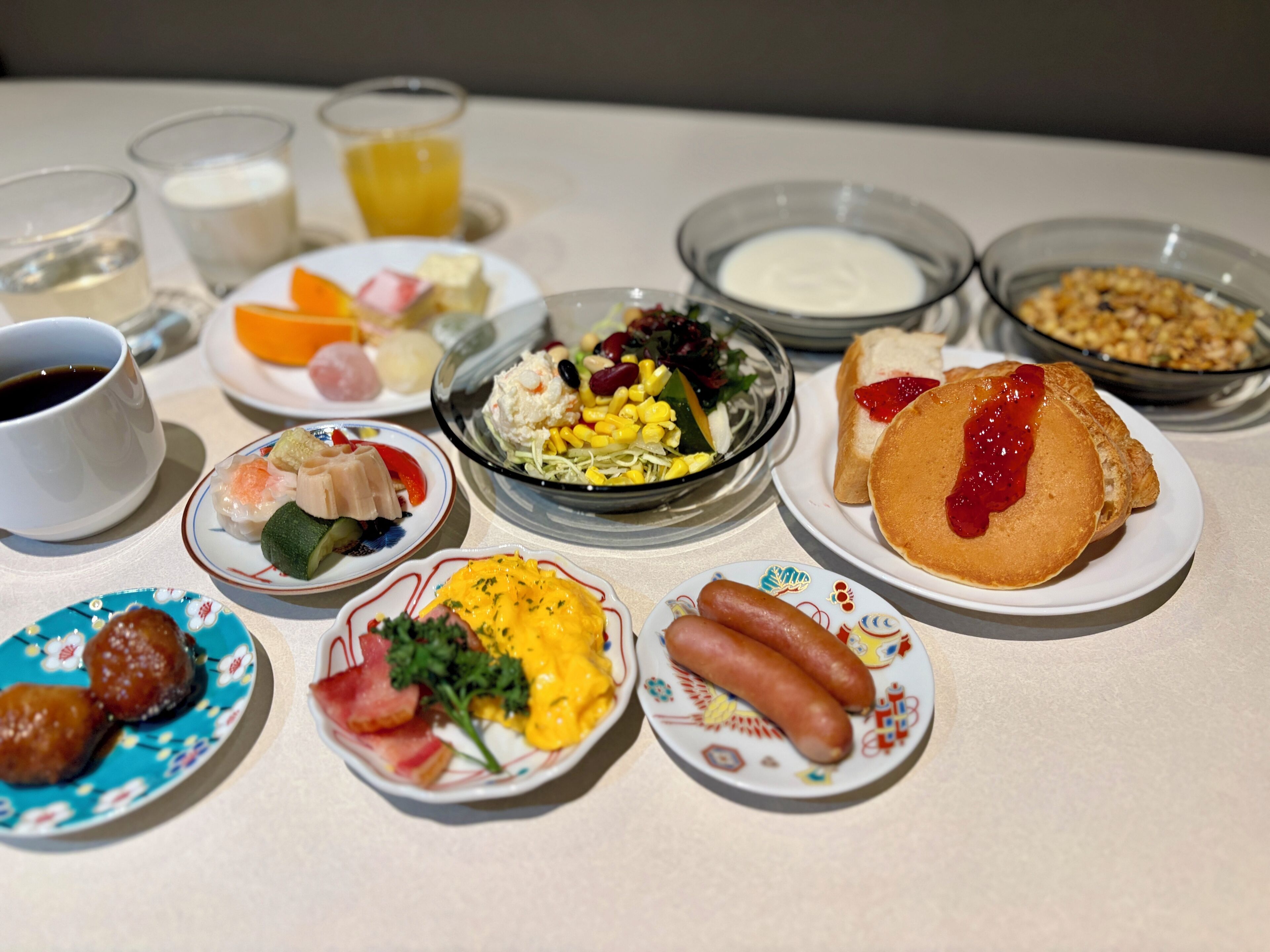 Uma mesa com diversos itens de café da manhã, incluindo panquecas, salsichas e uma salada.
