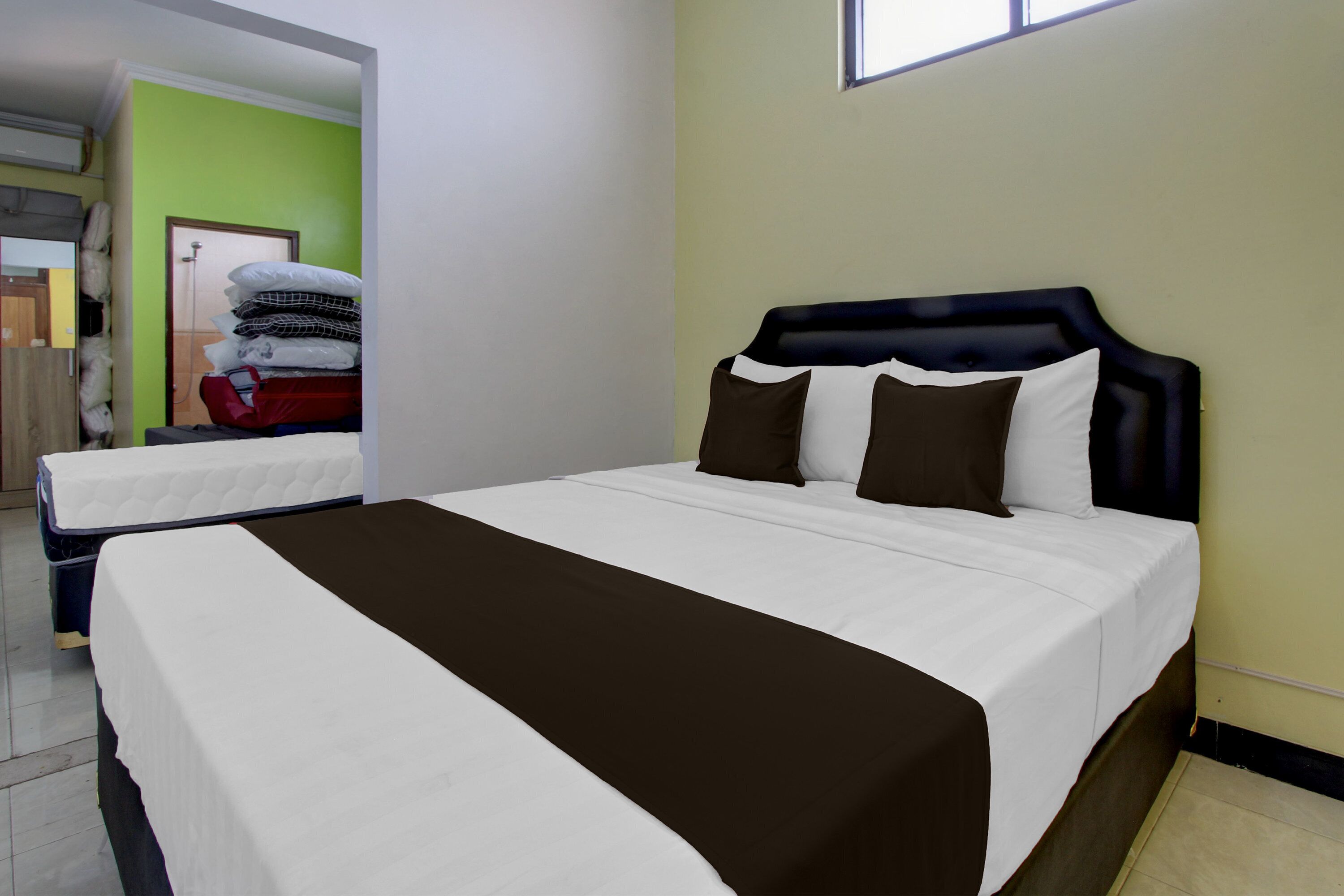 Quarto de hotel com uma cama grande, uma cama menor e banheiro à vista.