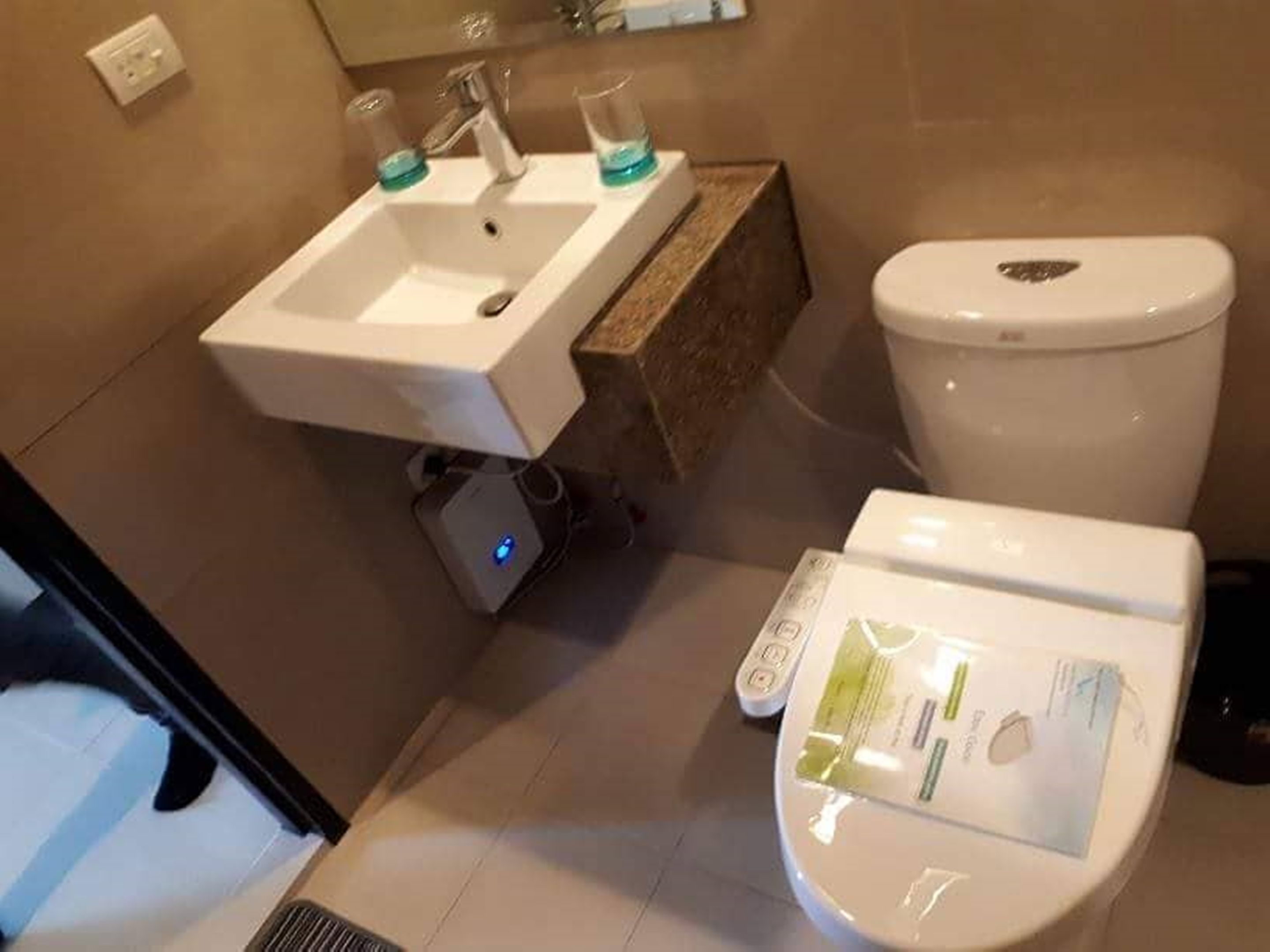 Uma casa de banho com uma pia branca, duas torneiras, sanita e zona de duche.