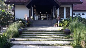 Um edifício com telhado escuro, entrada coberta e degraus até a porta.
