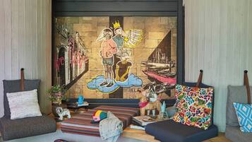 Uma sala de estar moderna com um grande mural, assentos confortáveis e um skate.