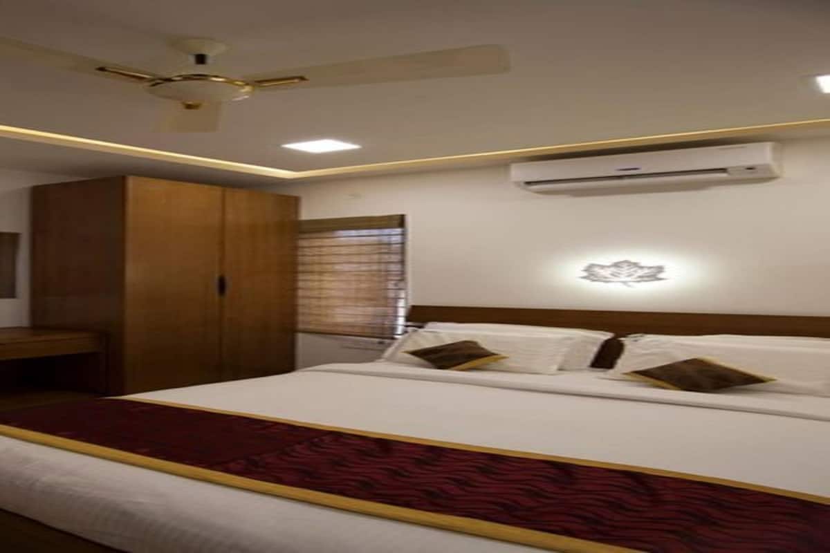 Quarto de hotel com cama, penteadeira com espelho, guarda-roupa e ar condicionado.