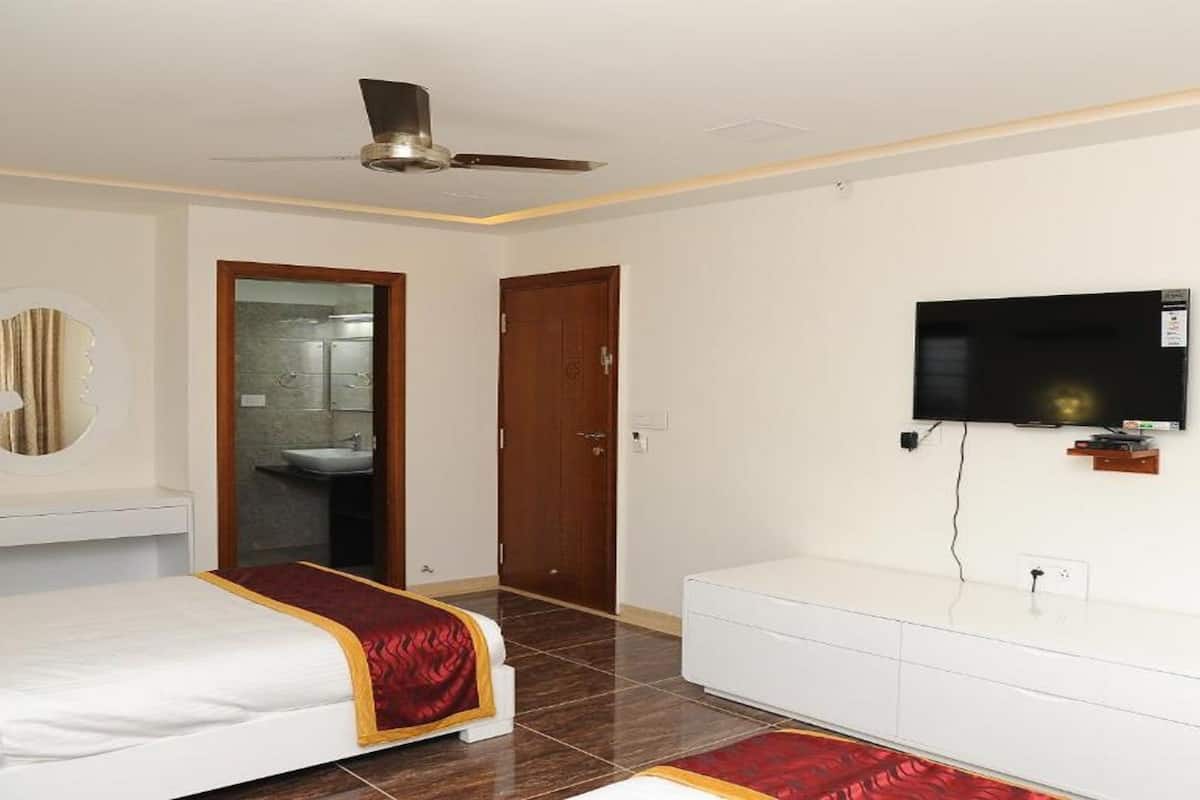 Quarto com uma cama, televisão, guarda-roupa e casa de banho visível por uma porta aberta.
