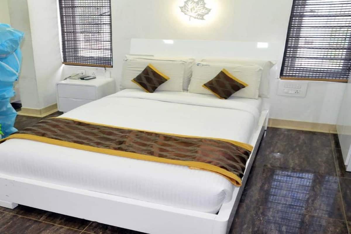 Quarto de hotel com cama, mesas de cabeceira e janela com persianas.