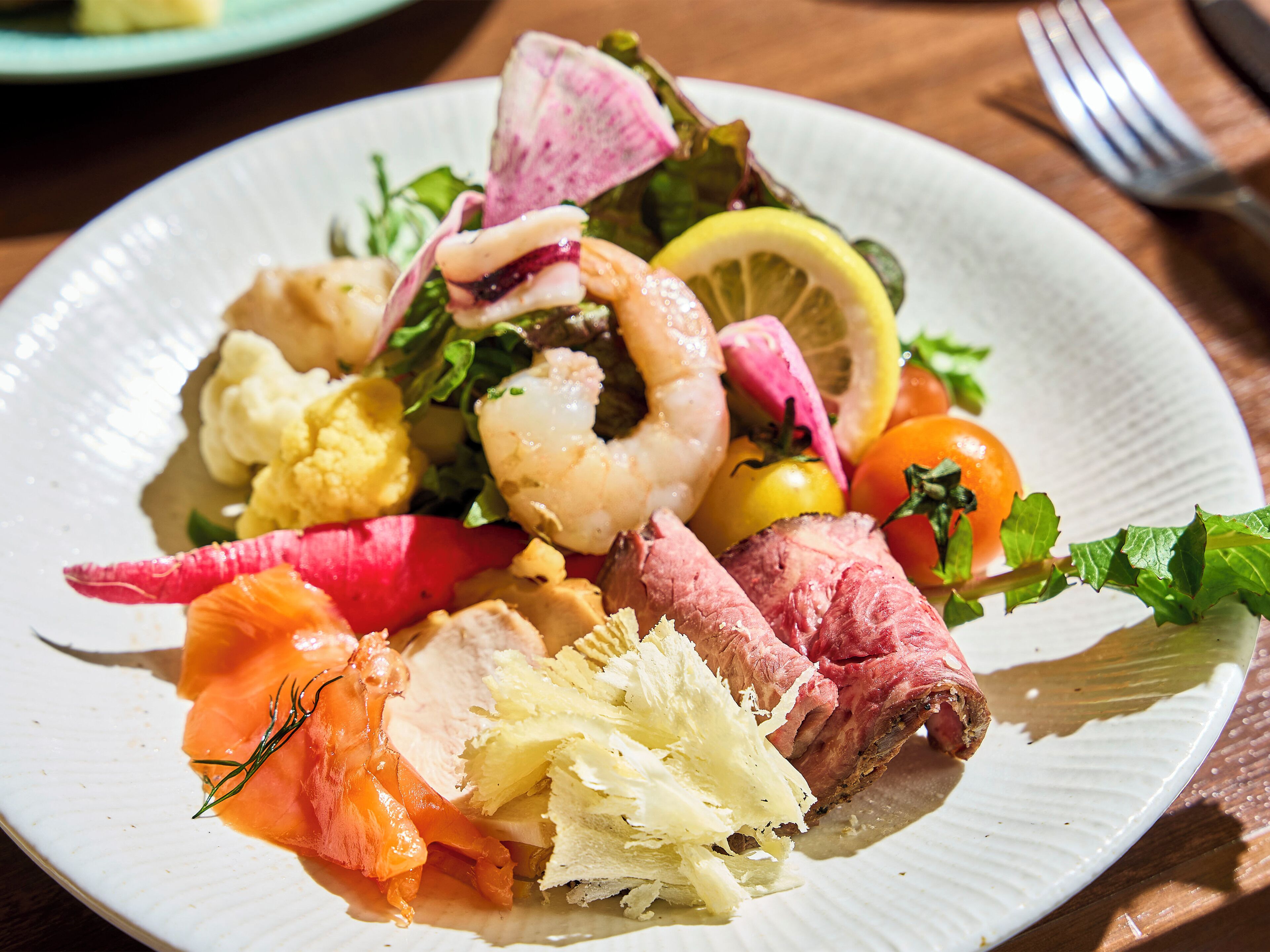 Um prato de comida com camarões, salmão e legumes.