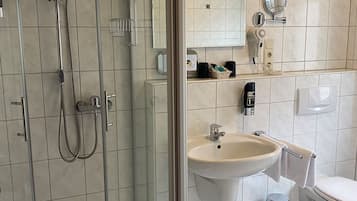 Um banheiro moderno com chuveiro em gabinete de vidro, pia e vaso sanitário.