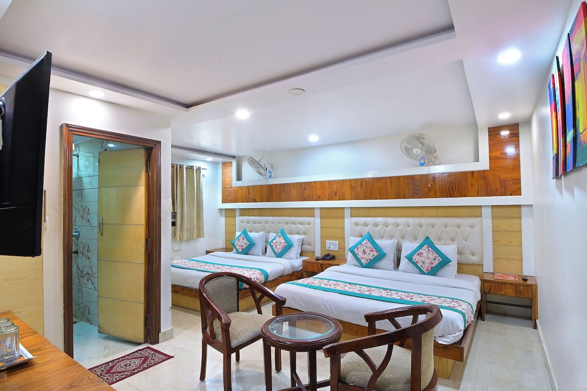 Quarto de hotel com duas camas, cabeceiras de madeira, uma mesa pequena e uma cadeira.