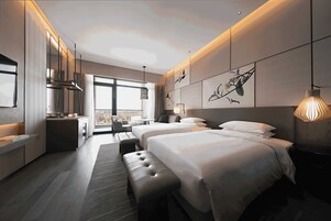 Quarto de hotel moderno com duas camas, um espaço de estar e vista para a cidade.