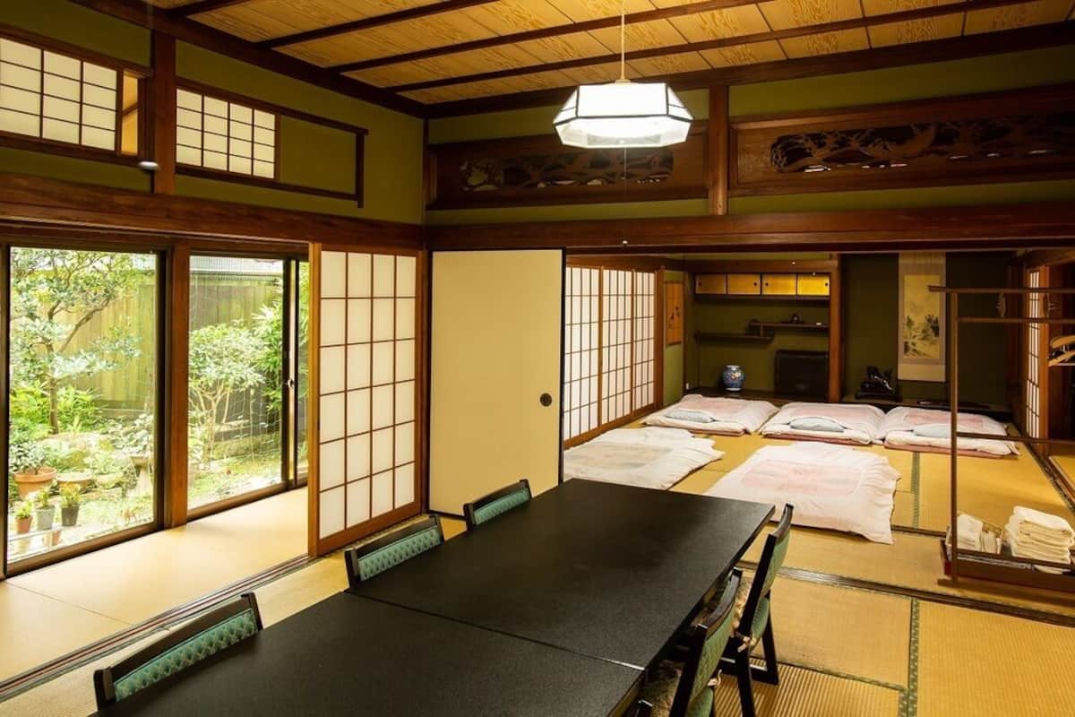 Um quarto japonês tradicional, com piso de tatame, portas deslizantes, uma mesa de tatame e um lustre.