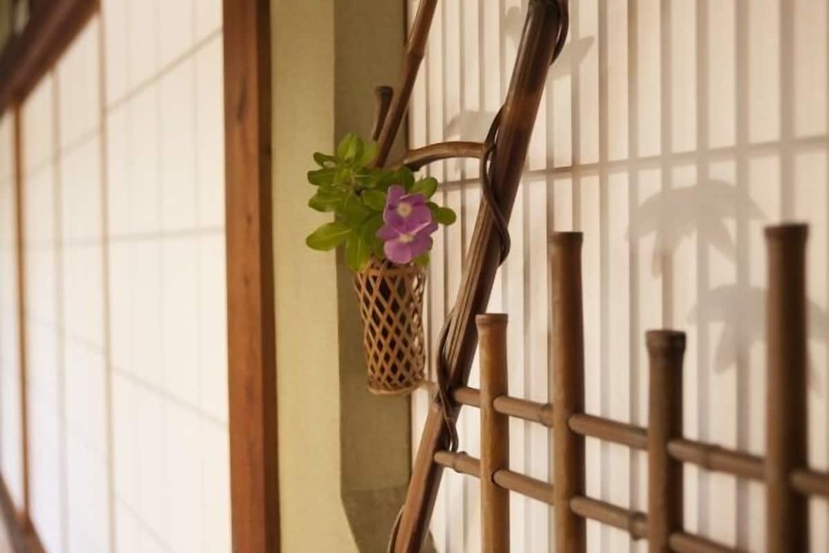 Uma divisória de bambu com uma cesta trançada contendo uma planta.