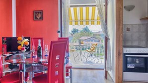 Uma área de refeições com mesa de vidro, cadeiras vermelhas e parede vermelha.