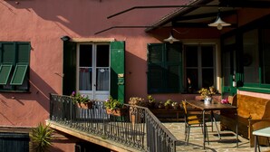 Um edifício com varanda, mesas ao ar livre e uma placa indicando um restaurante.