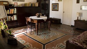 Um quarto com uma mesa de jantar, cadeiras, uma estante, um armário e um tapete estampado.