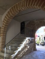 Uma escadaria com um arco de pedra, dando acesso a um segundo andar.