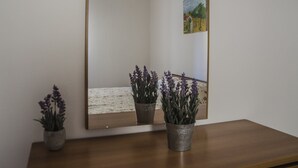 Um espelho reflete uma mesa de madeira com três plantas em vasos.