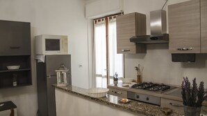 Cozinha moderna com micro-ondas embutido, eletrodomésticos de aço inoxidável, fogão a gás e armários de madeira.