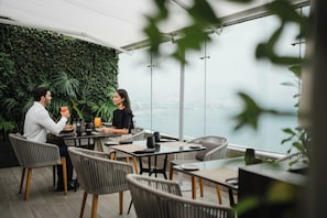 Uma sala de jantar com mesas, cadeiras e vista para a cidade.