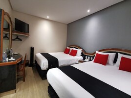 Quarto de hotel com duas camas, uma mesa com cadeira, televisão fixada na parede e um espelho.