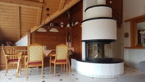 Um quarto acolhedor com teto de madeira, lareira, uma mesa de jantar com cadeiras e um espelho na parede.