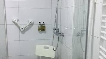 Uma área de chuveiro com porta de vidro, uma cadeira branca e um secador de mãos.