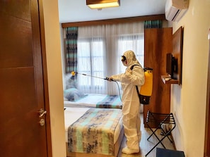 Uma pessoa com roupa de proteção pulverizando um quarto.