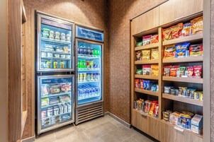 Espaço de venda automática com várias prateleiras repletas de petiscos e bebidas.