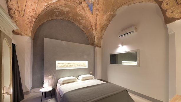 Um quarto moderno com uma cama grande, uma mesa pequena, um espelho e teto em arco.