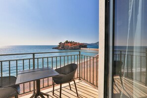 Varanda com mesa e cadeiras, vista para o litoral e um edifício histórico.
