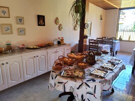 Uma área de refeições com mesa de buffet, armários brancos e decorações nas paredes.