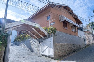 Uma casa de dois andares com portão fechado, uma placa com o nome 