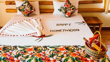 Uma cama com colcha florida e a mensagem "HAPPY HONEYMOON".