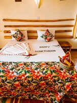 Uma cama com colcha florida e a mensagem "HAPPY HONEYMOON".