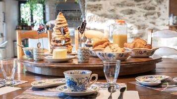 Uma mesa de café da manhã com diversos doces, uma cafeteira e uma saladeira de frutas.