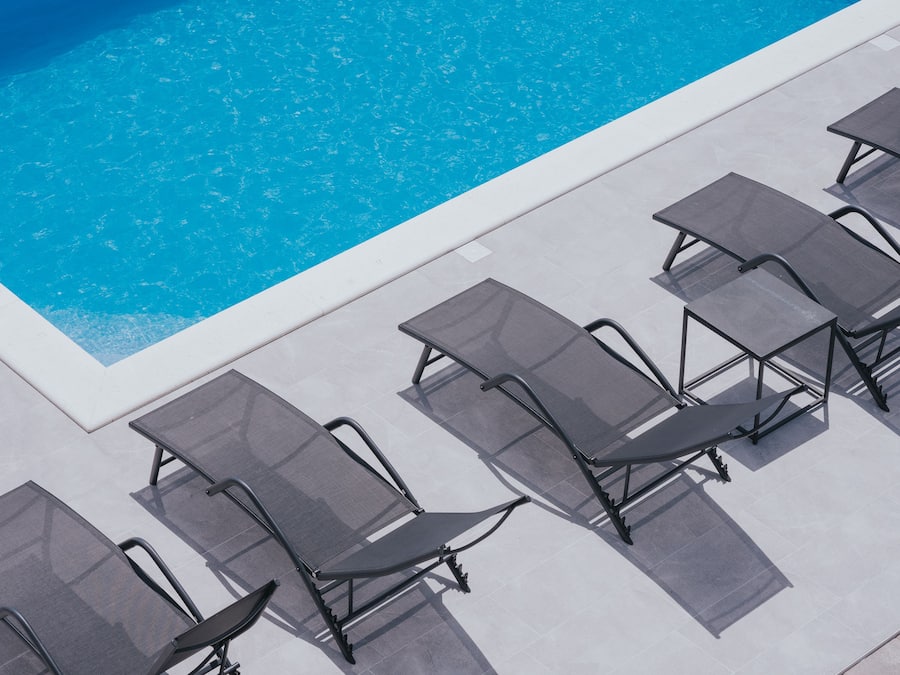 Uma área à beira da piscina com espreguiçadeiras e uma piscina azul cristalina.