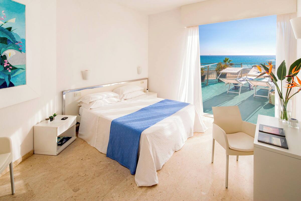 Quarto de hotel com uma cama, uma escrivaninha e vista para o oceano.