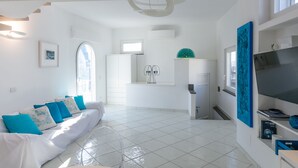 Uma sala de estar moderna com um sofá branco, uma área de refeições com um armário branco e uma janela grande.