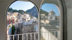 Vista da janela sobre um horizonte urbano com edifícios e uma montanha.