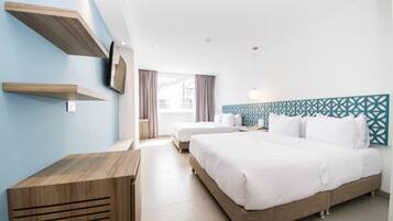 Quarto de hotel moderno com uma cama grande, uma escrivaninha e uma TV fixada na parede.