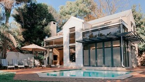 Uma casa moderna com piscina, varanda coberta e gramado bem cuidado.