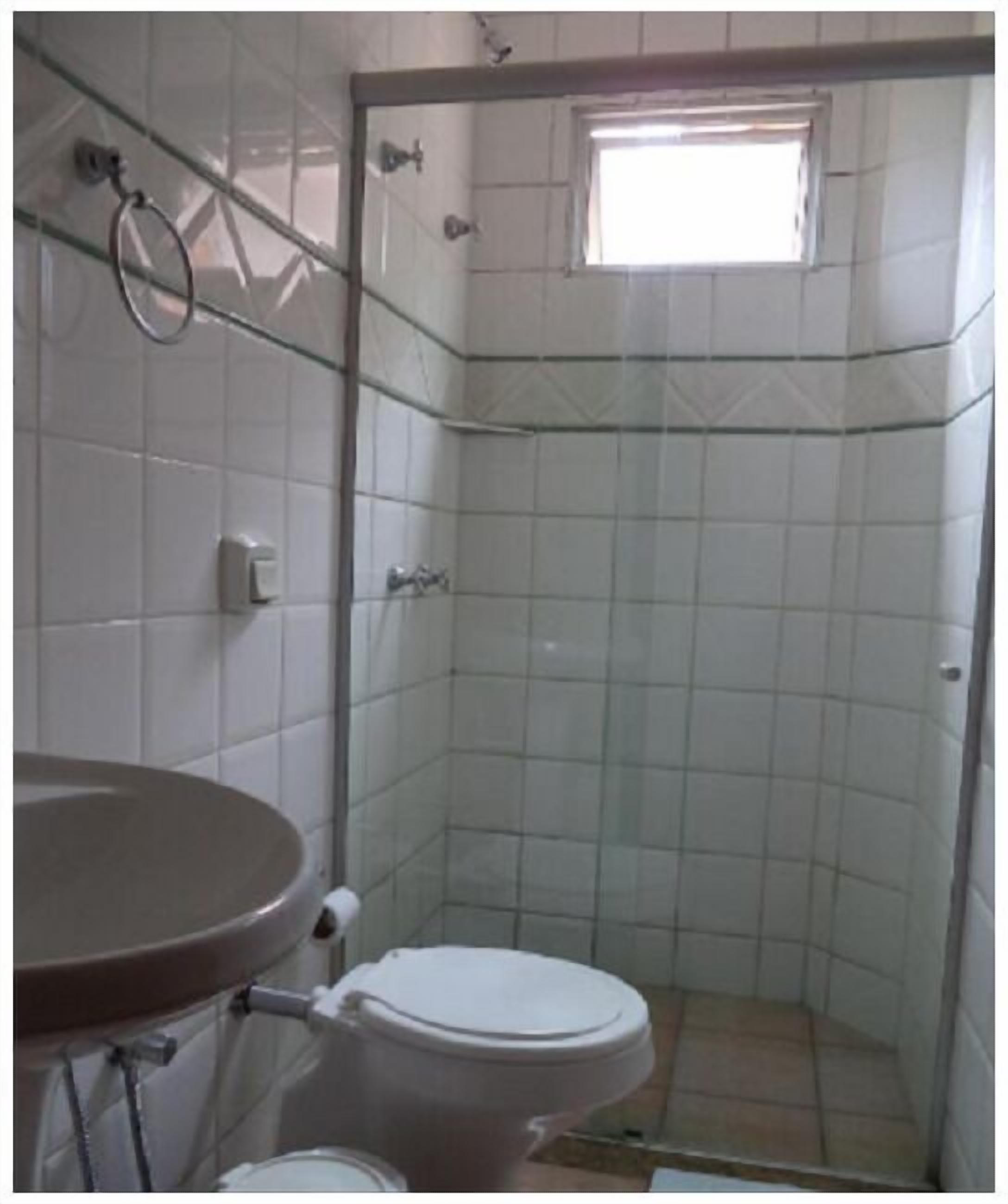 Uma casa de banho pequena com azulejos, com sanita, lavatório e chuveiro.