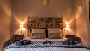 Uma cama com cabeceira estampada, duas luminárias de cabeceira e um chifre de veado fixado na parede.