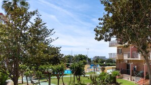 Pátio com piscina, palmeiras e parquinho.