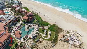 Vista aérea de um resort com uma grande piscina, área de praia e vários edifícios.